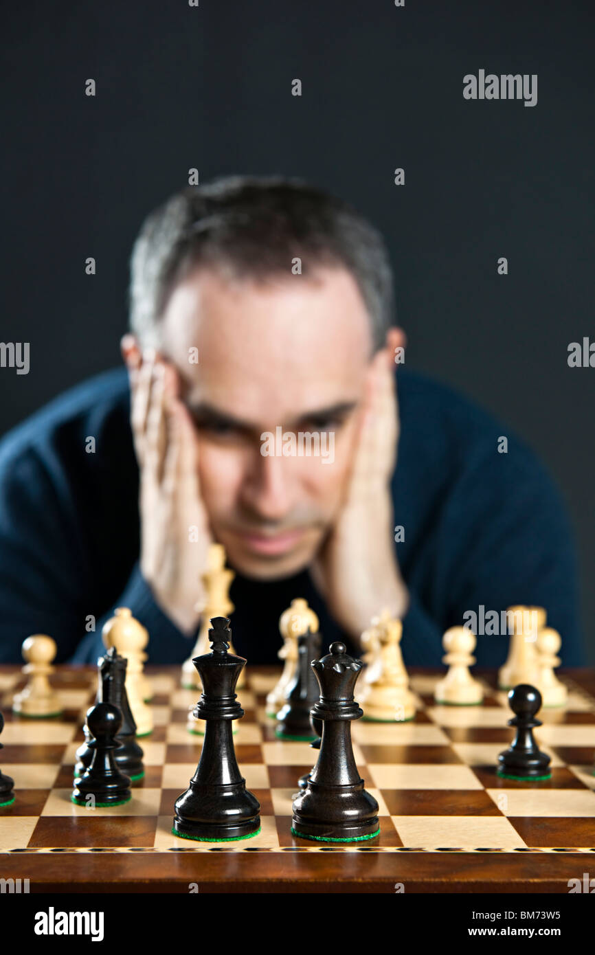 Chessboard with man thinking about chess strategy Stock Photo - Alamy