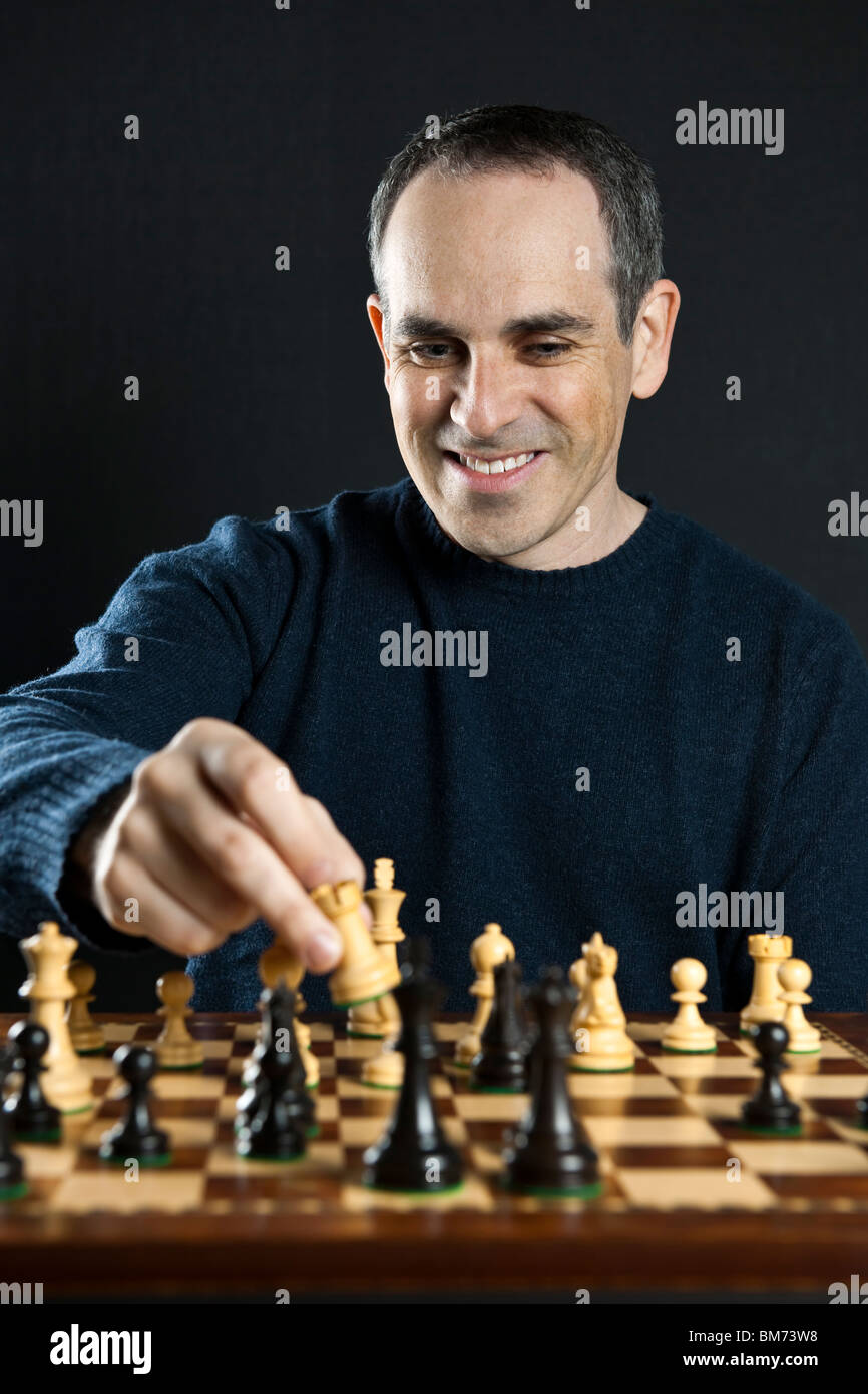 Man moving a chess piece to win the game Stock Photo - Alamy