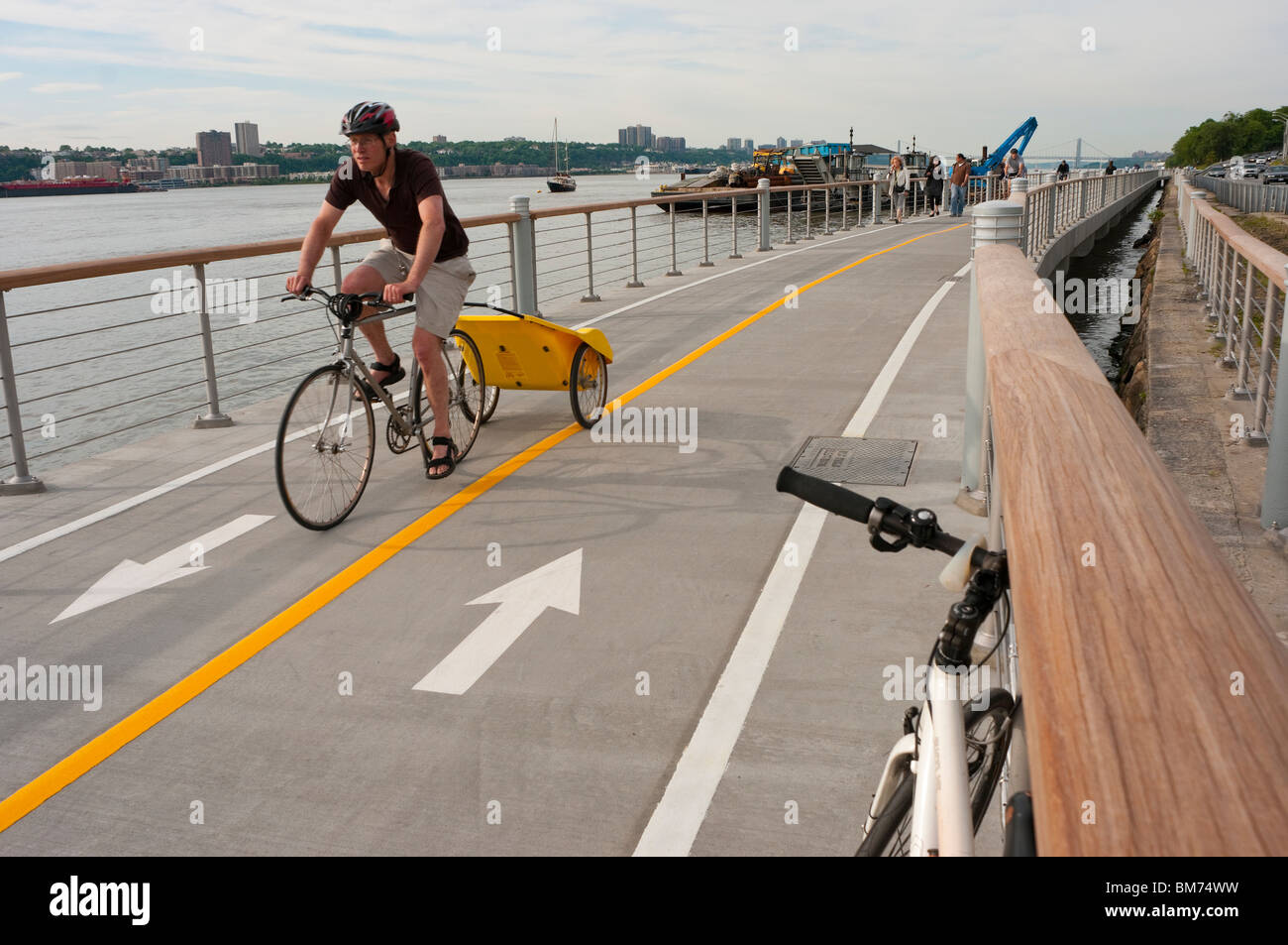 Man on a bicycle pulling a utility trailer riding on Riverwalk Stock ...