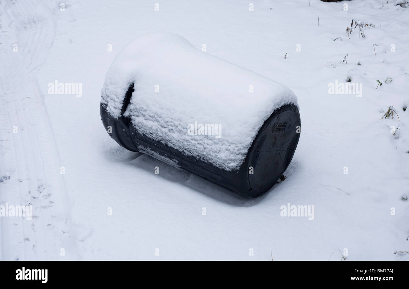 A black dustbin lies in its side in the snow on an atypically cold ...