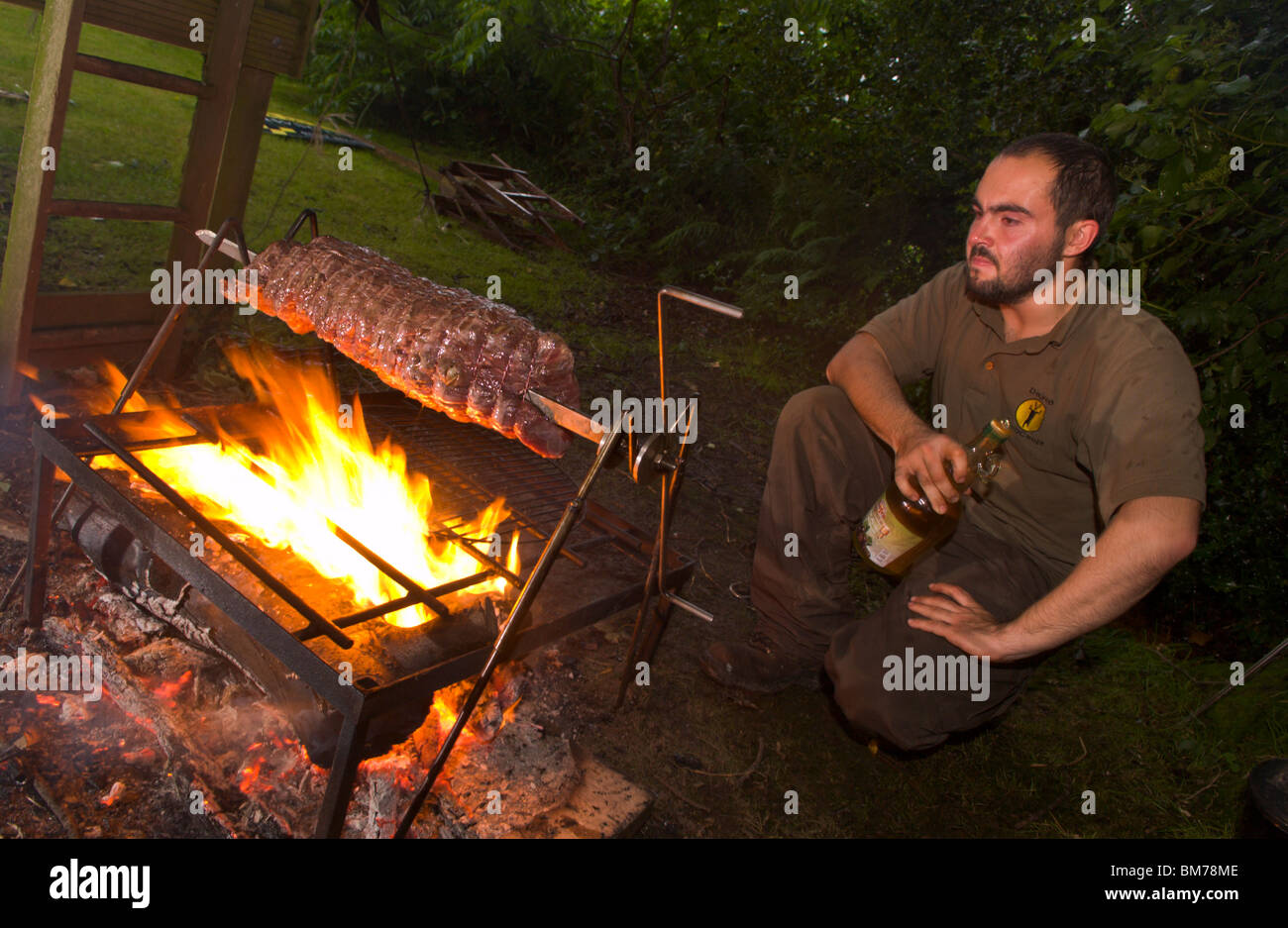 Roll of beef being cooked on spit over open fire at barbecue on Gower ...