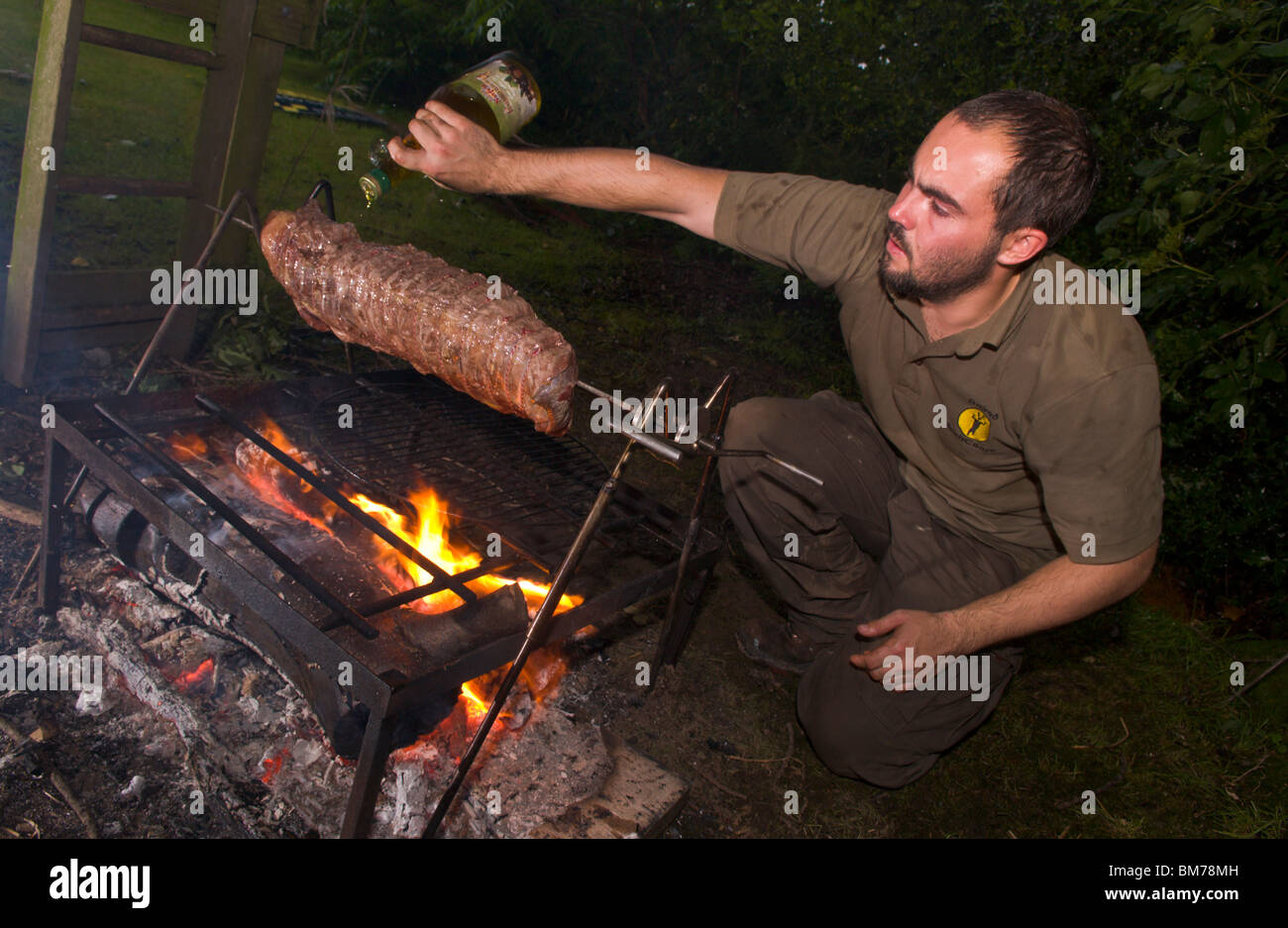 Roll of beef being cooked on spit over open fire at barbecue on Gower ...