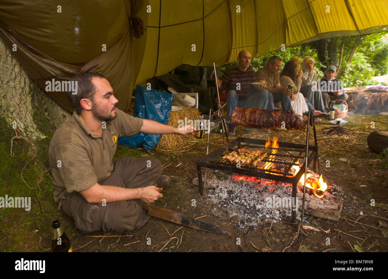 Roll of beef being cooked on spit over open fire at barbecue on Gower ...