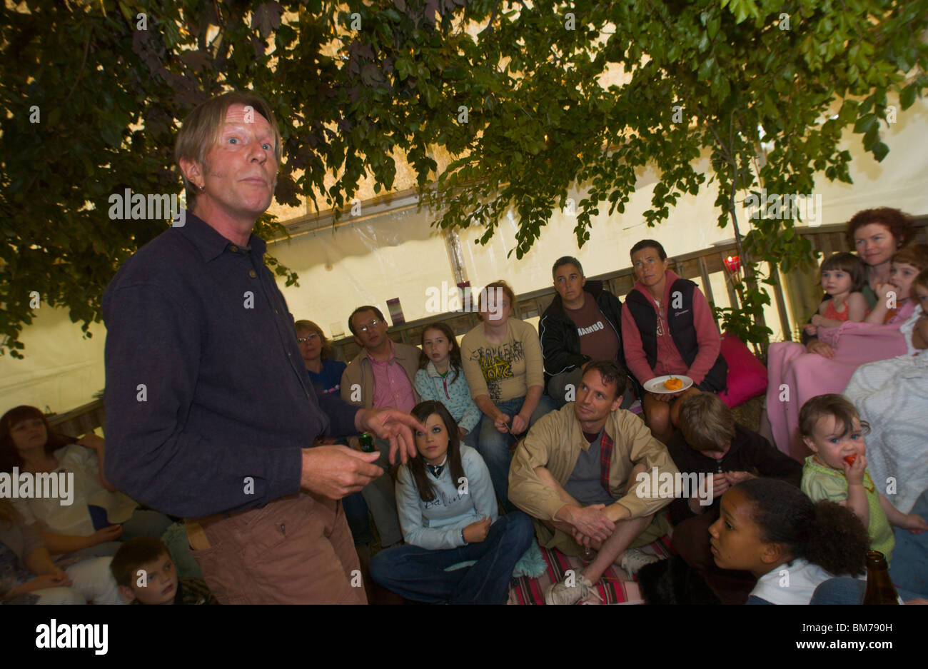 Storyteller performing for group of children and adults at party on ...