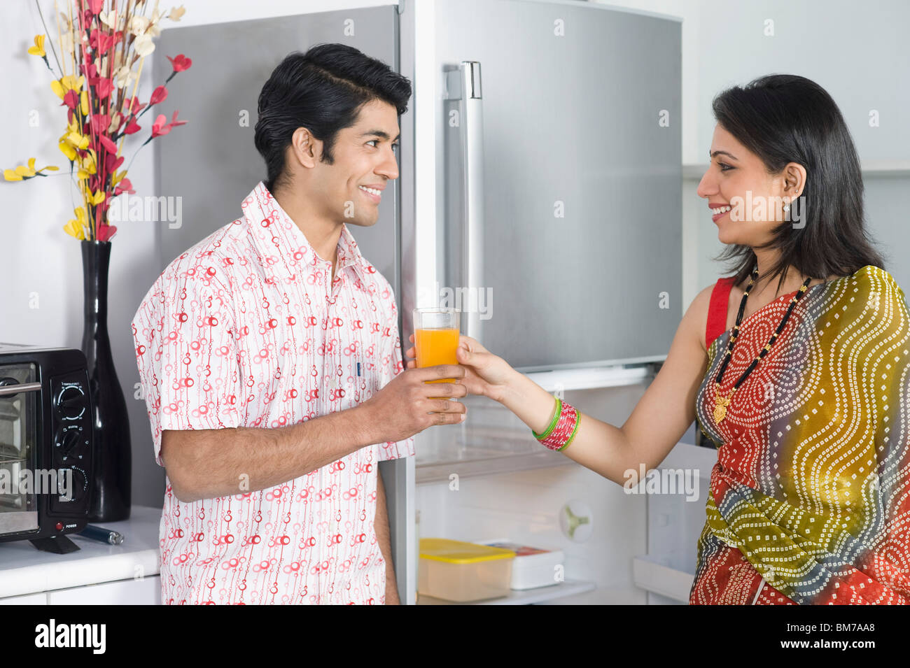 Woman giving orange juice to a man Stock Photo - Alamy