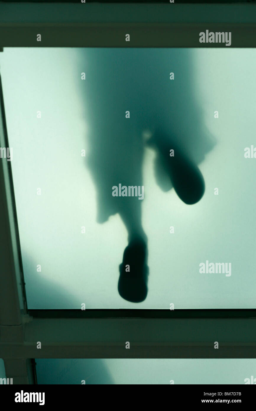 Legs and feet seen through a glass flooring, directly below Stock Photo ...