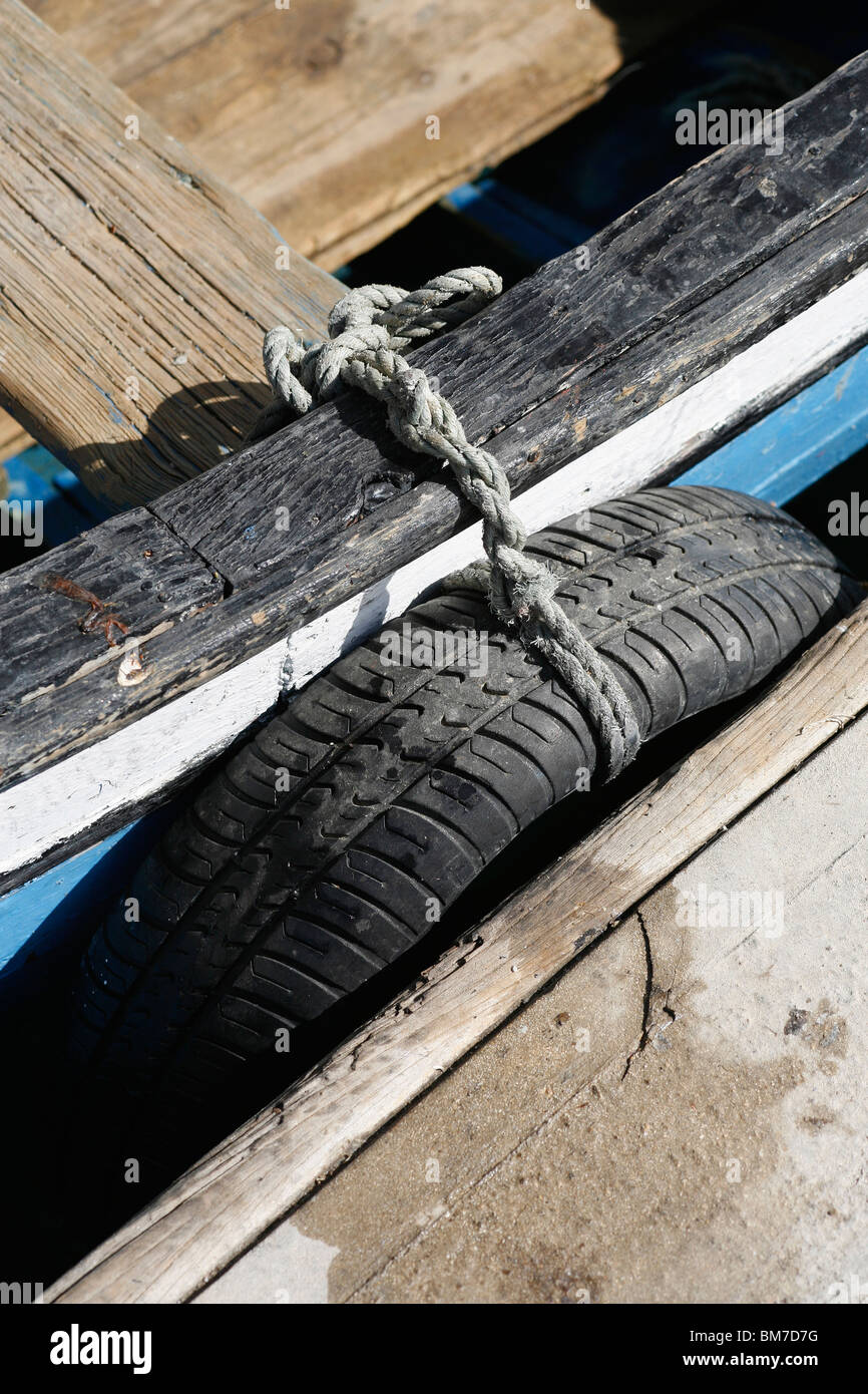 A tire tied to a boat docked at a jetty Stock Photo - Alamy