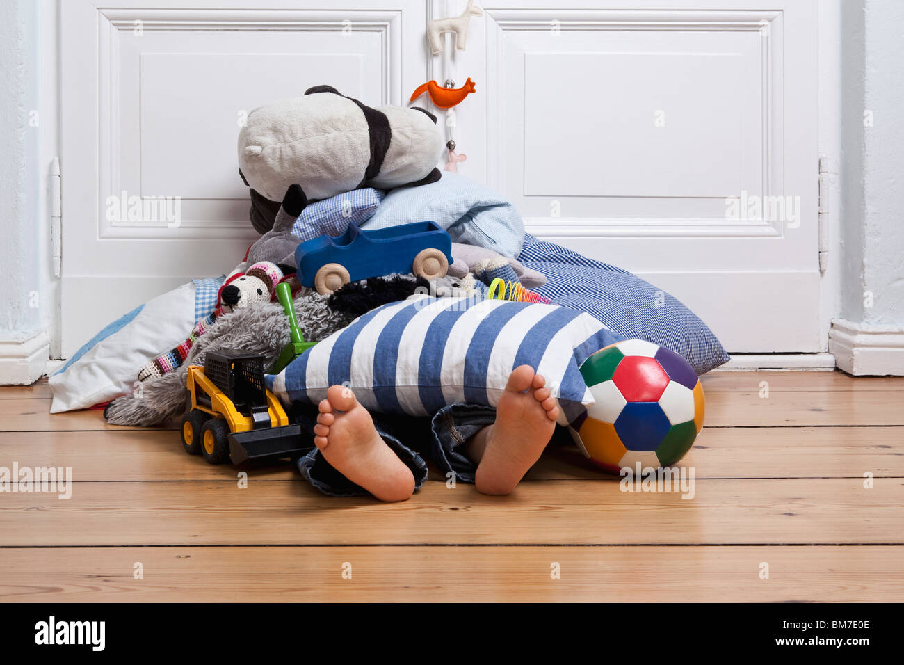 A child covered in toys, only feet visible Stock Photo - Alamy