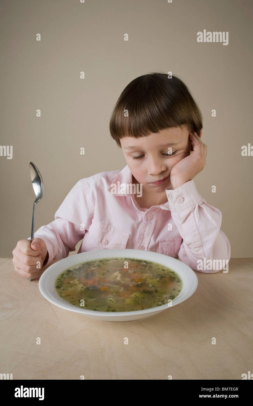 A boy looking disappointedly at a bowl of vegetable soup Stock Photo ...
