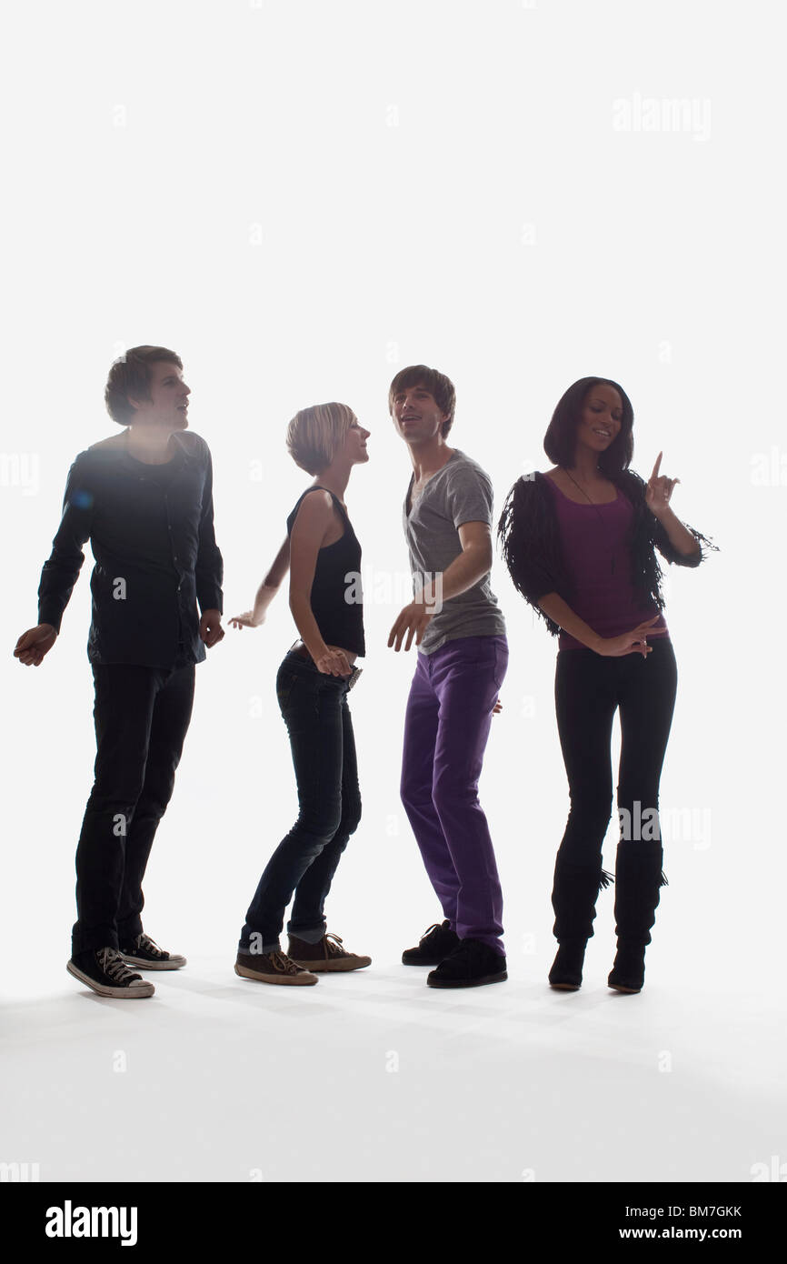 Four young people dancing, studio shot, white background, back lit ...