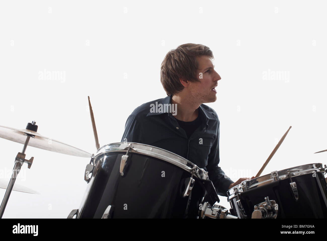 A man playing the drums, studio shot, white background, back lit Stock ...