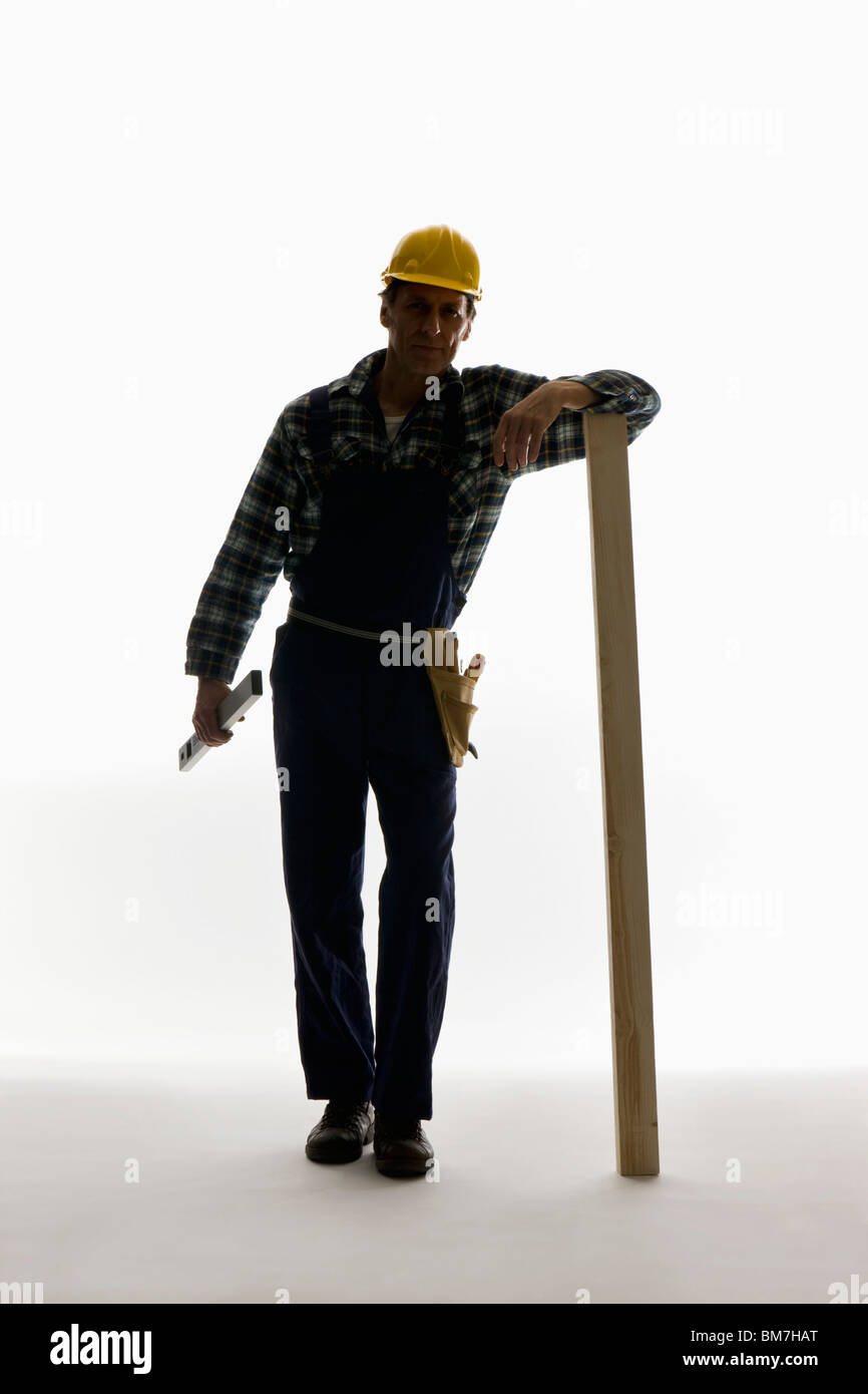A construction worker carrying a level and leaning on a plank Stock ...