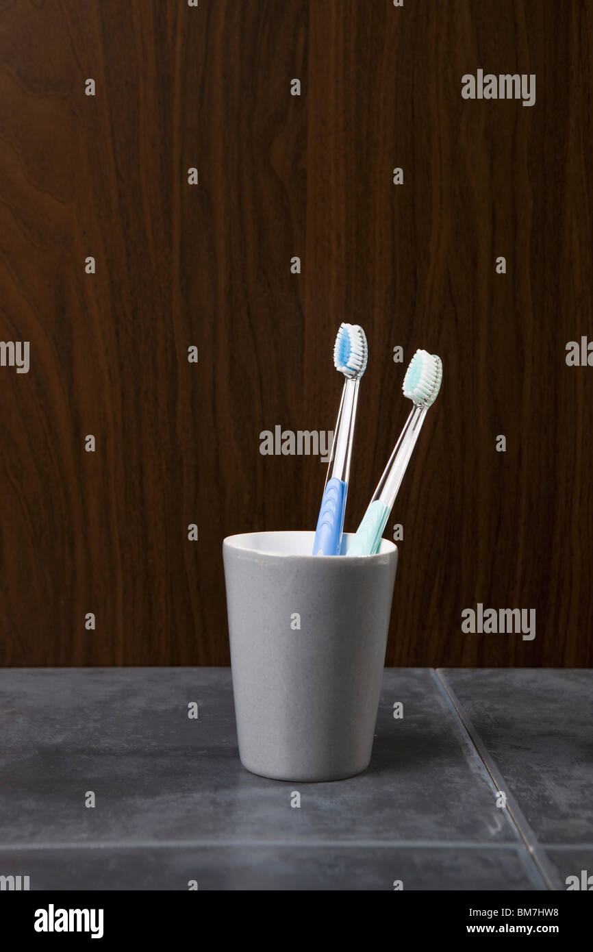 Two toothbrushes in a ceramic cup Stock Photo - Alamy