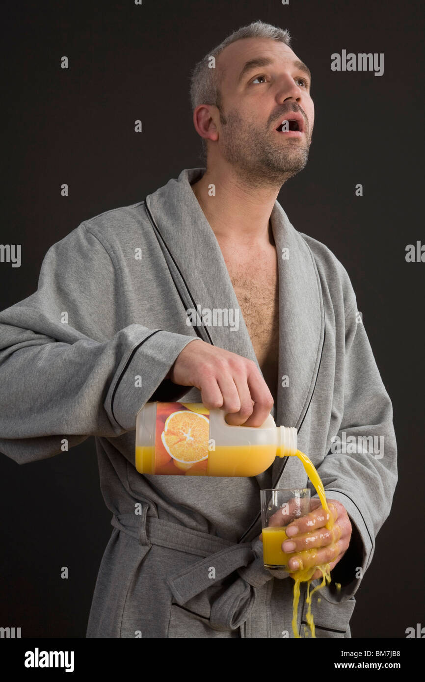 A man pouring orange juice into a glass and spilling it Stock Photo - Alamy
