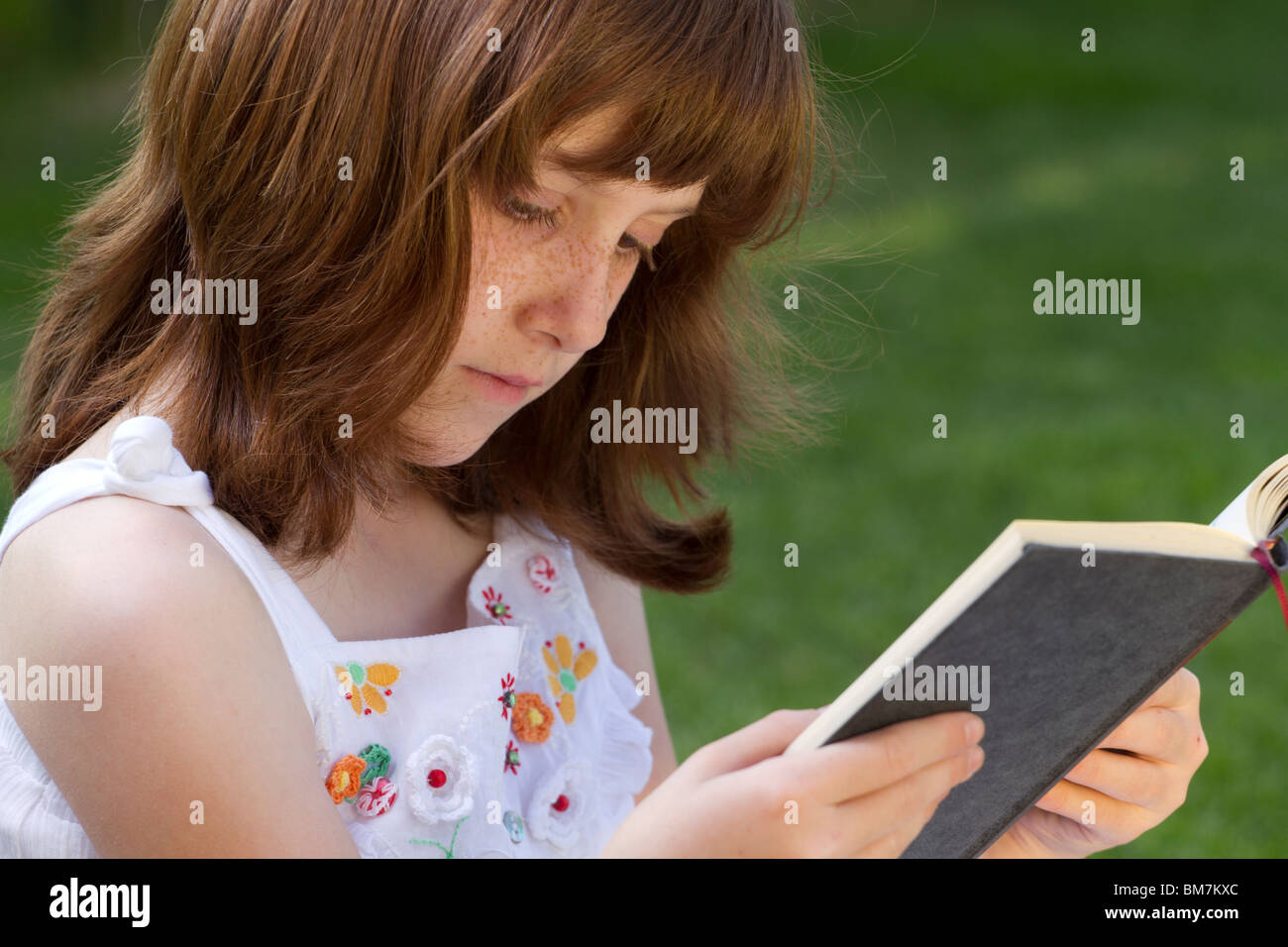 Young beautiful girl reading a book outdoor Stock Photo - Alamy