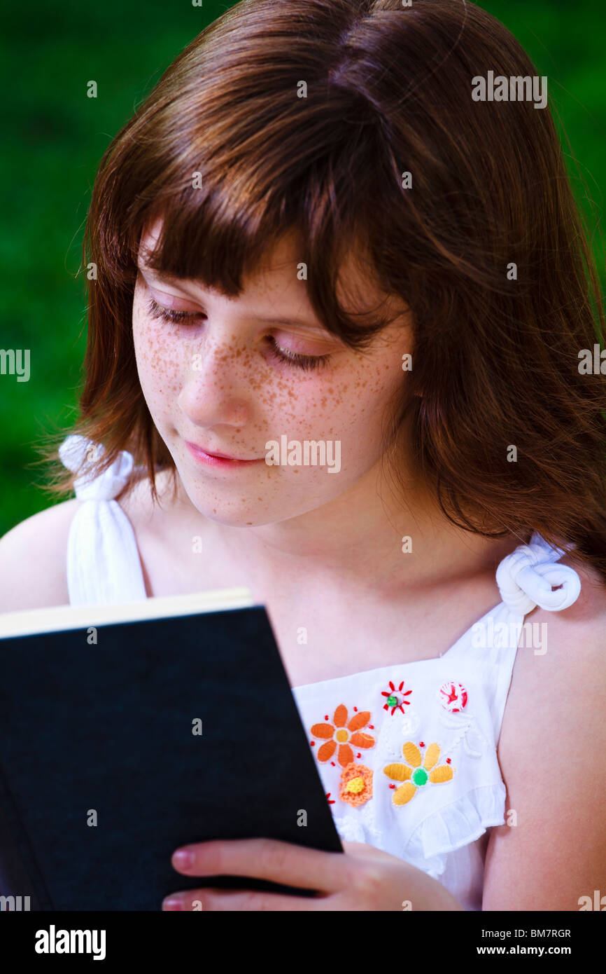 Young beautiful girl reading a book outdoor Stock Photo - Alamy