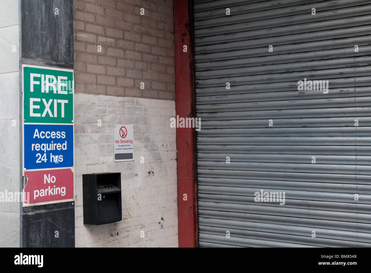 A fire exit sign next to shutters that requires 24 hour access Stock ...