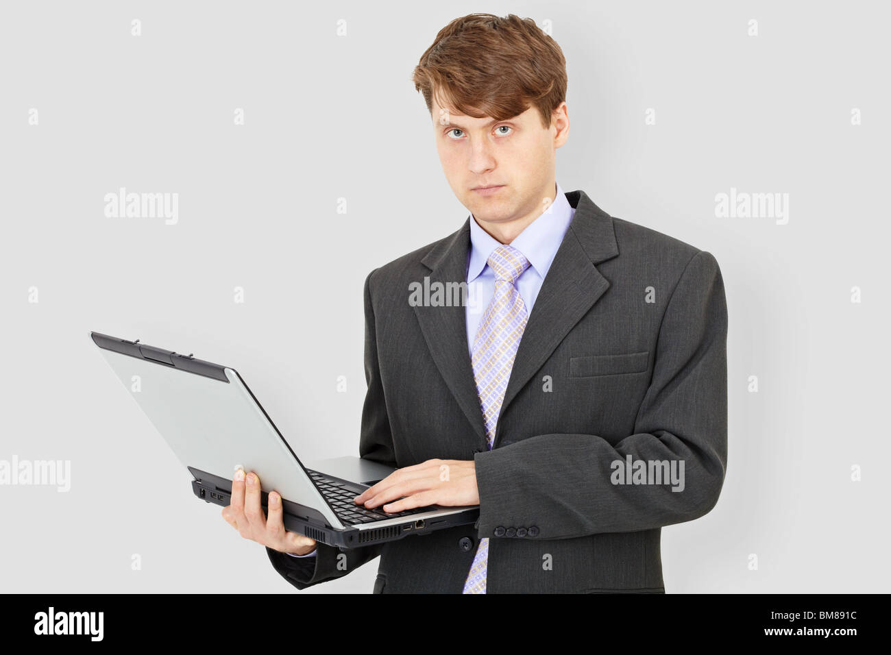 The business man with the laptop on a grey background Stock Photo - Alamy