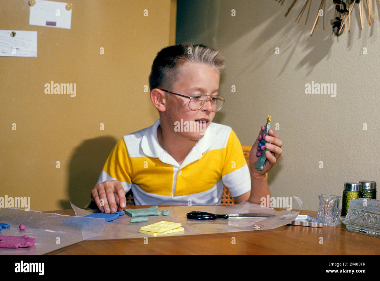 Young blond boy creates model with colored plastic clay art make male ...