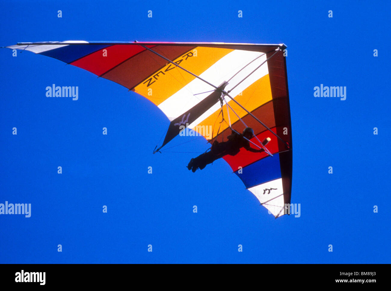 Colorful nylon hang-glider soars overhead helmet safe sport fly fun ...
