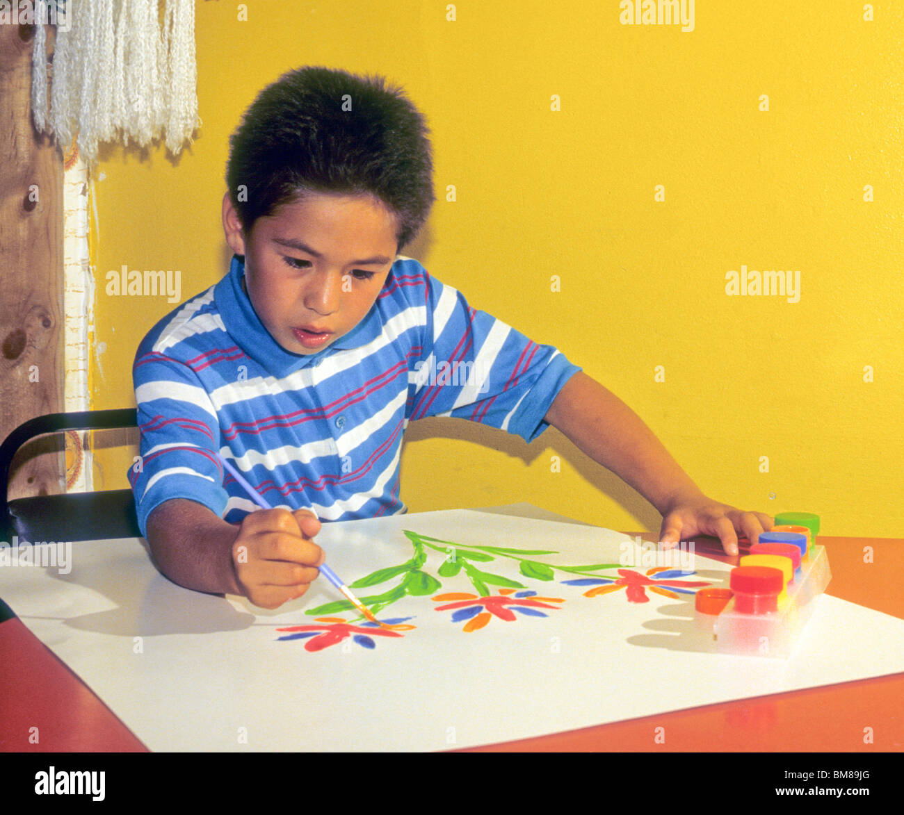 Hispanic boy paints colored flowers serious intent art decorate fun ...