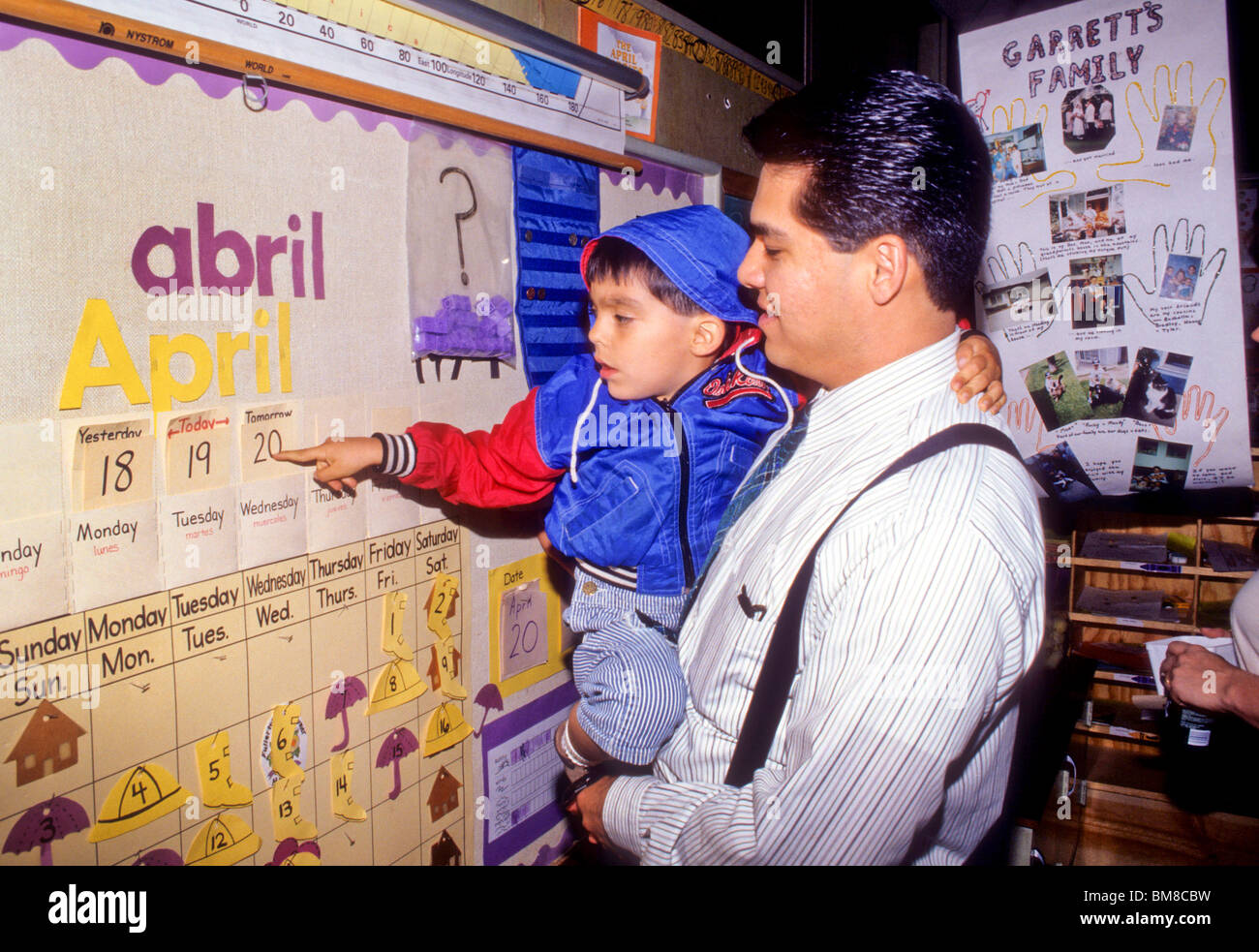 Hispanic boy points to his school work on display as father looks on ...