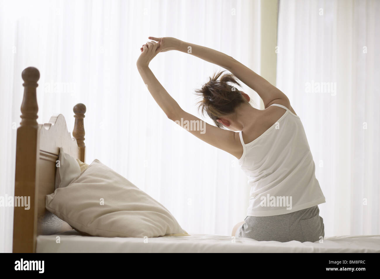Young woman stretching on bed Stock Photo - Alamy