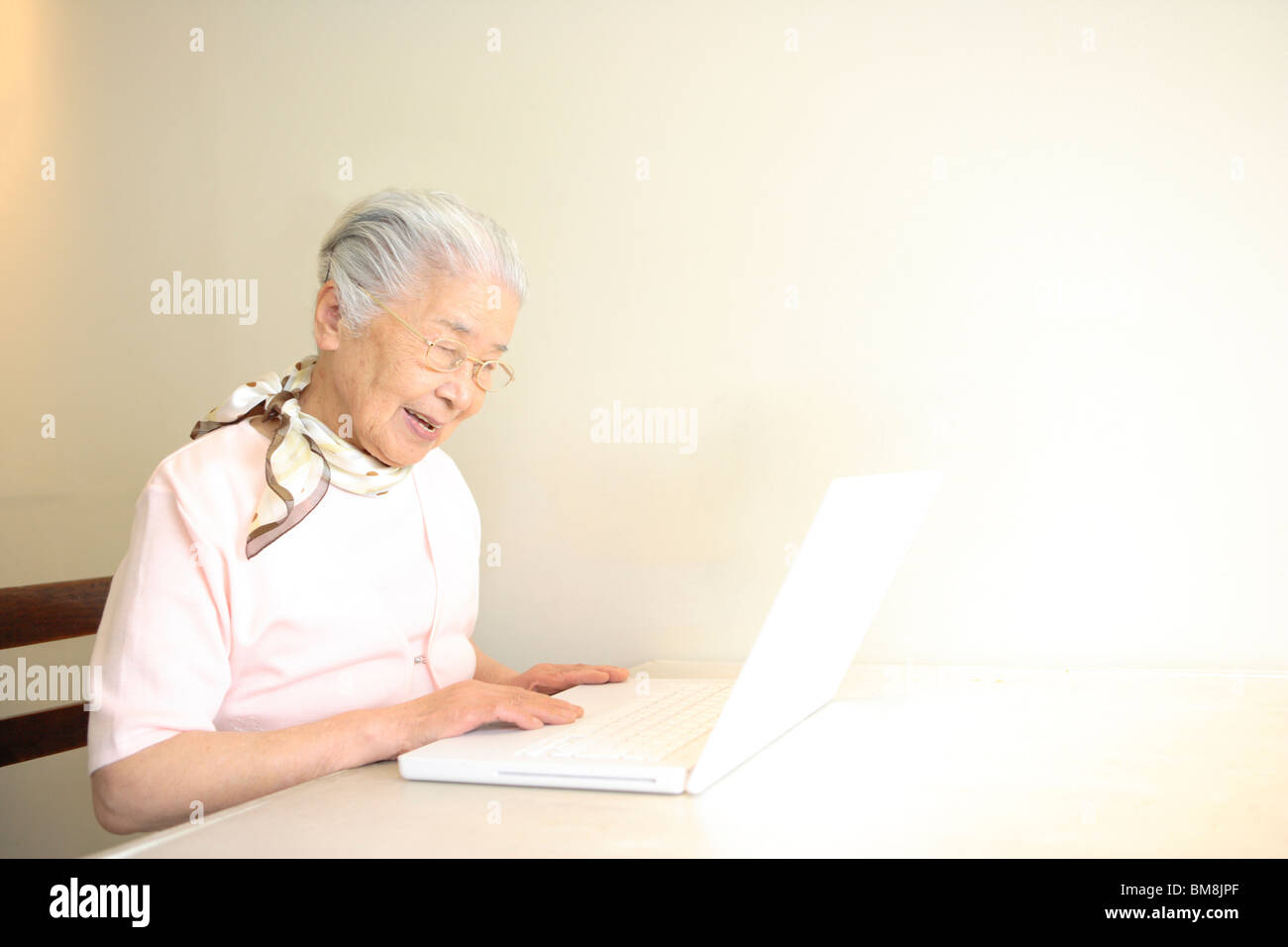 Senior woman using laptop, smiling, white background Stock Photo - Alamy