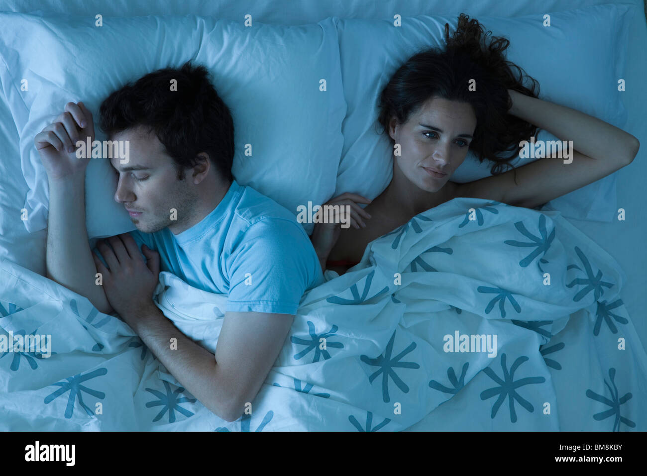 Couple lying together in bed, woman restlessly awake looking away Stock ...