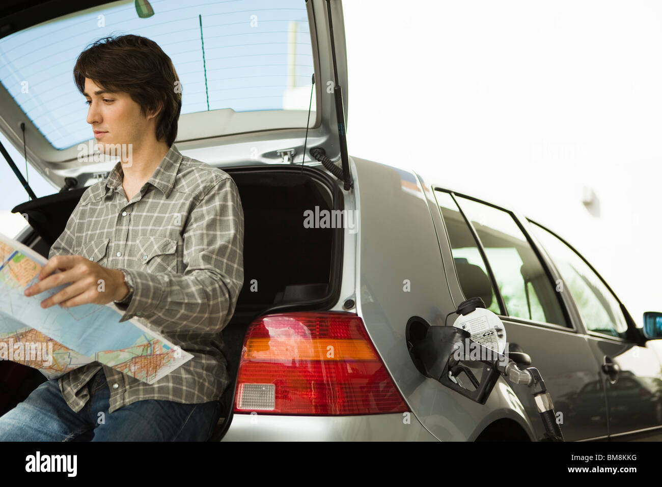 At gas station refueling, checking map Stock Photo - Alamy