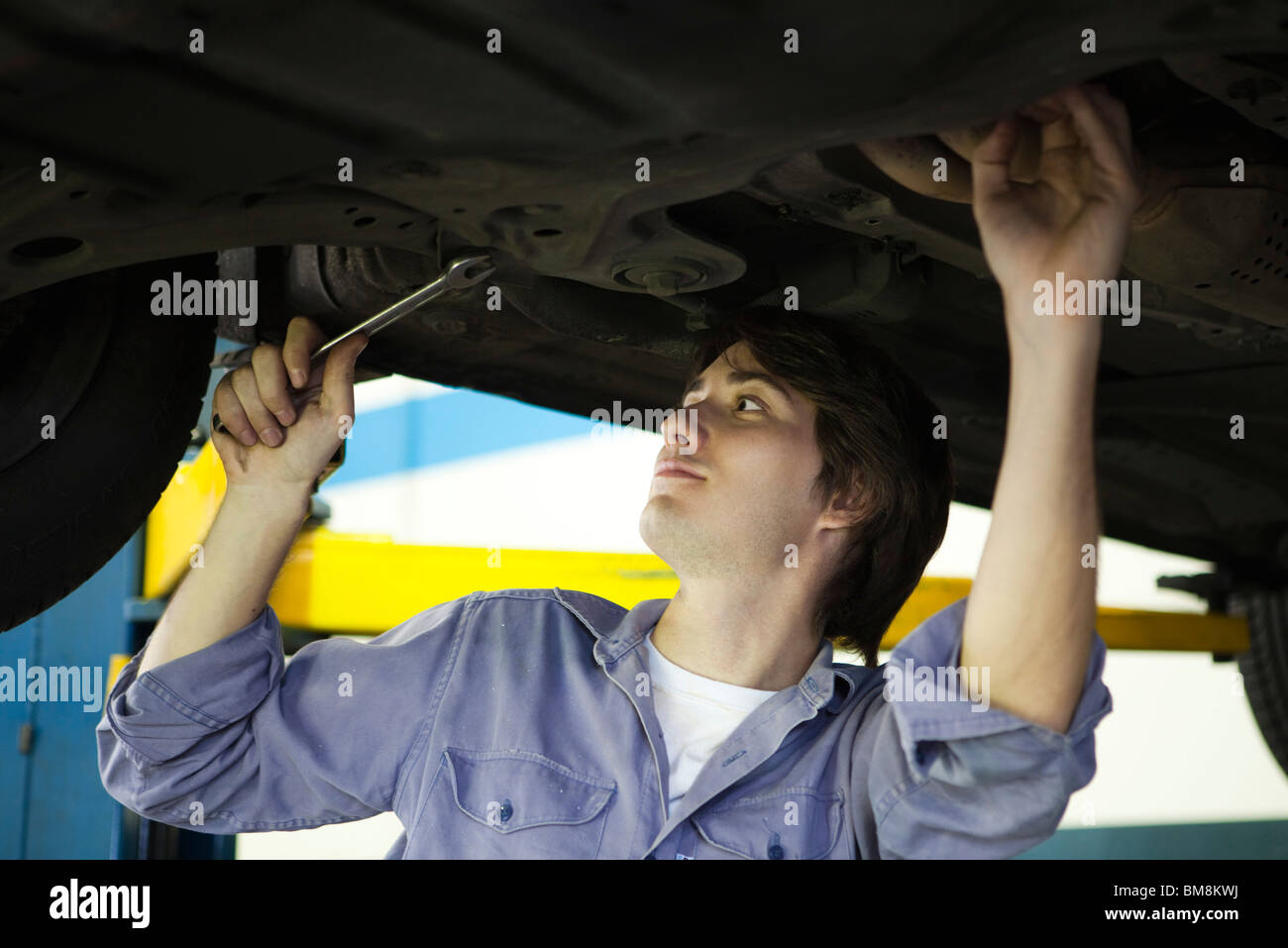 Mechanic working on underside of car elevated on hydraulic lift Stock ...