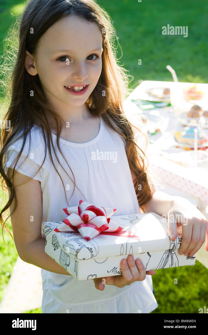 Girl at birthday party holding wrapped gift Stock Photo - Alamy