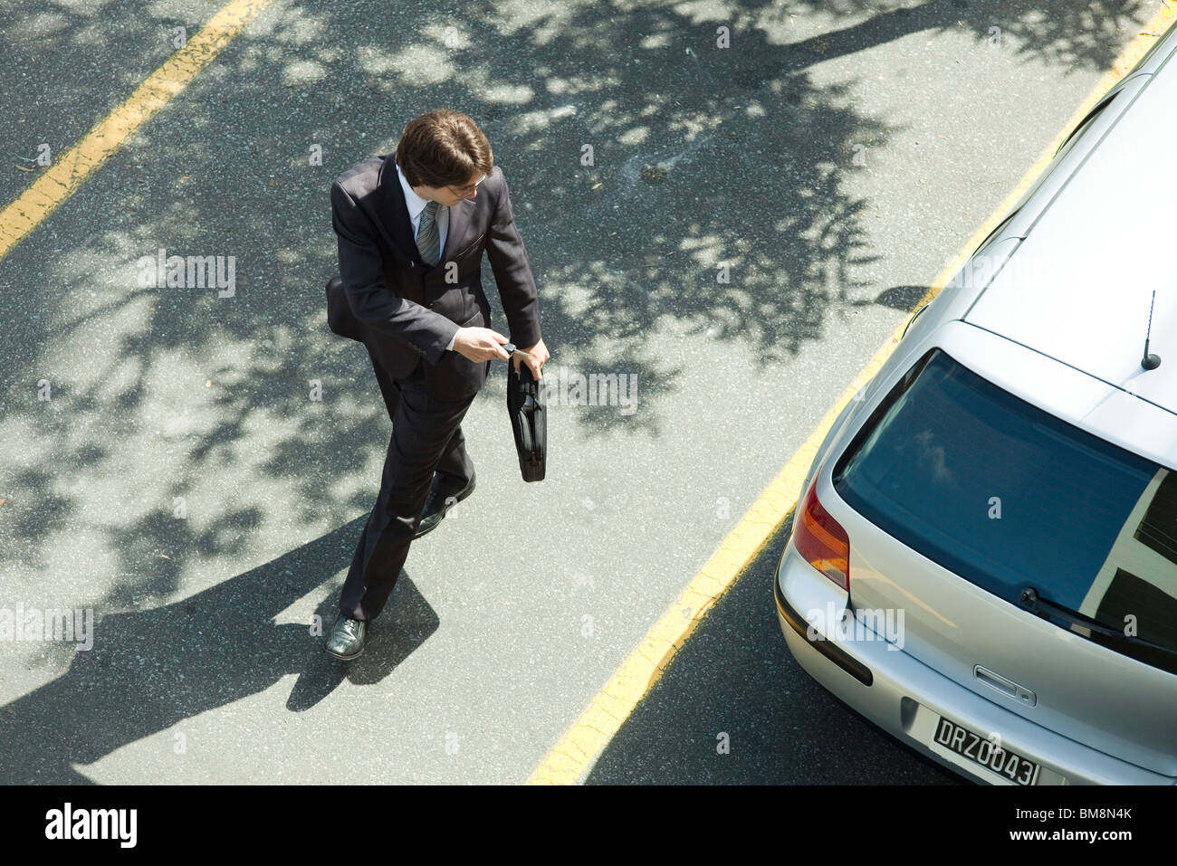Man locking car doors using key remote as he walks away Stock Photo - Alamy