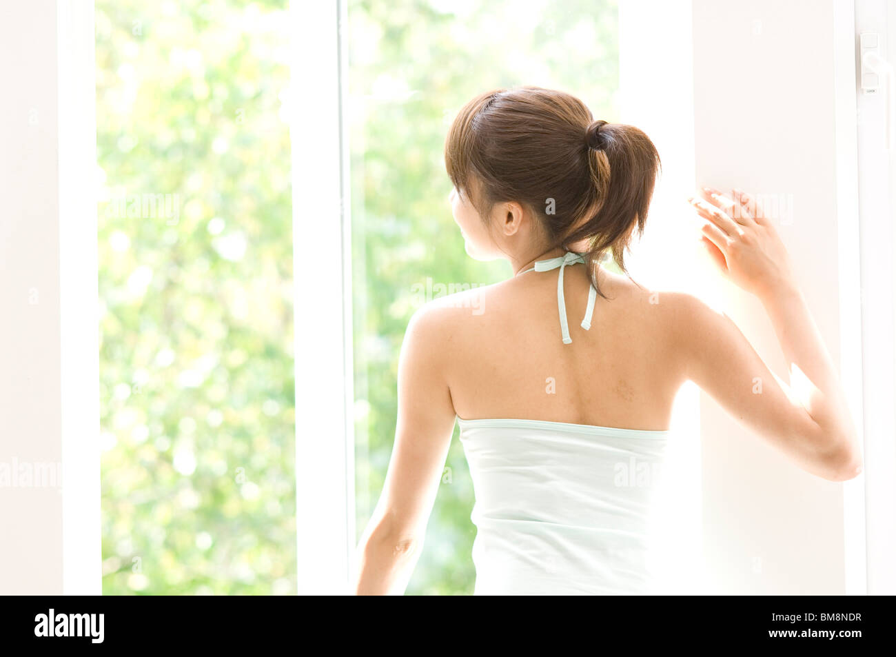 Young woman looking out the window Stock Photo - Alamy