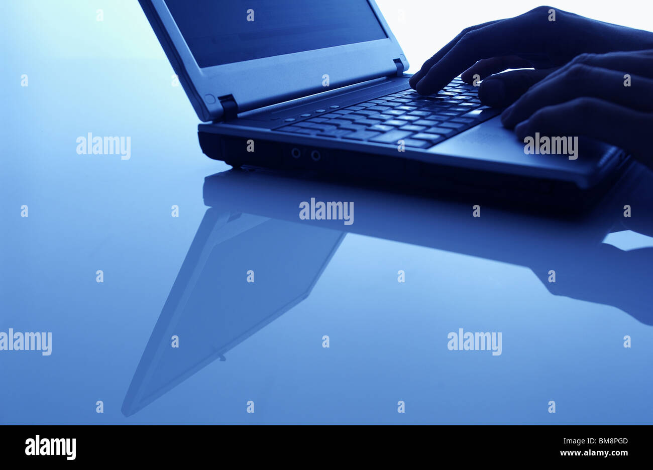 Hand using laptop blue background Stock Photo - Alamy