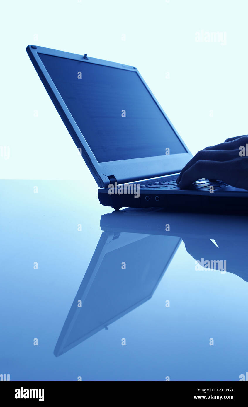 Hand using laptop blue background Stock Photo - Alamy