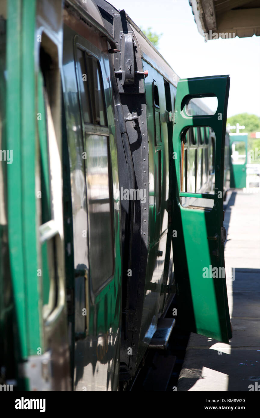 A railway train standing at a station platform with carriage doors open ...