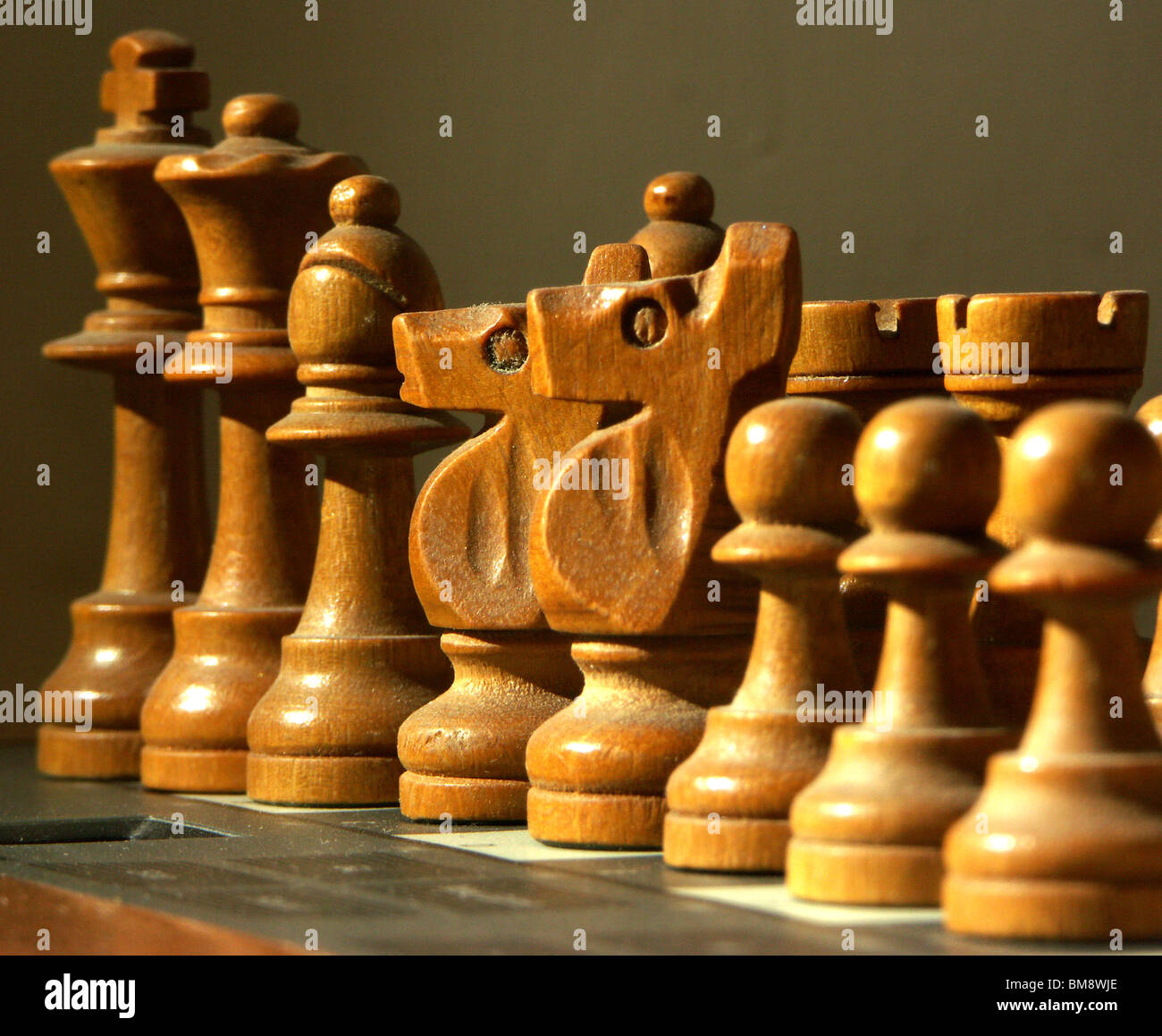 close-up of chess pieces dusty illuminated by light side aligned in ...