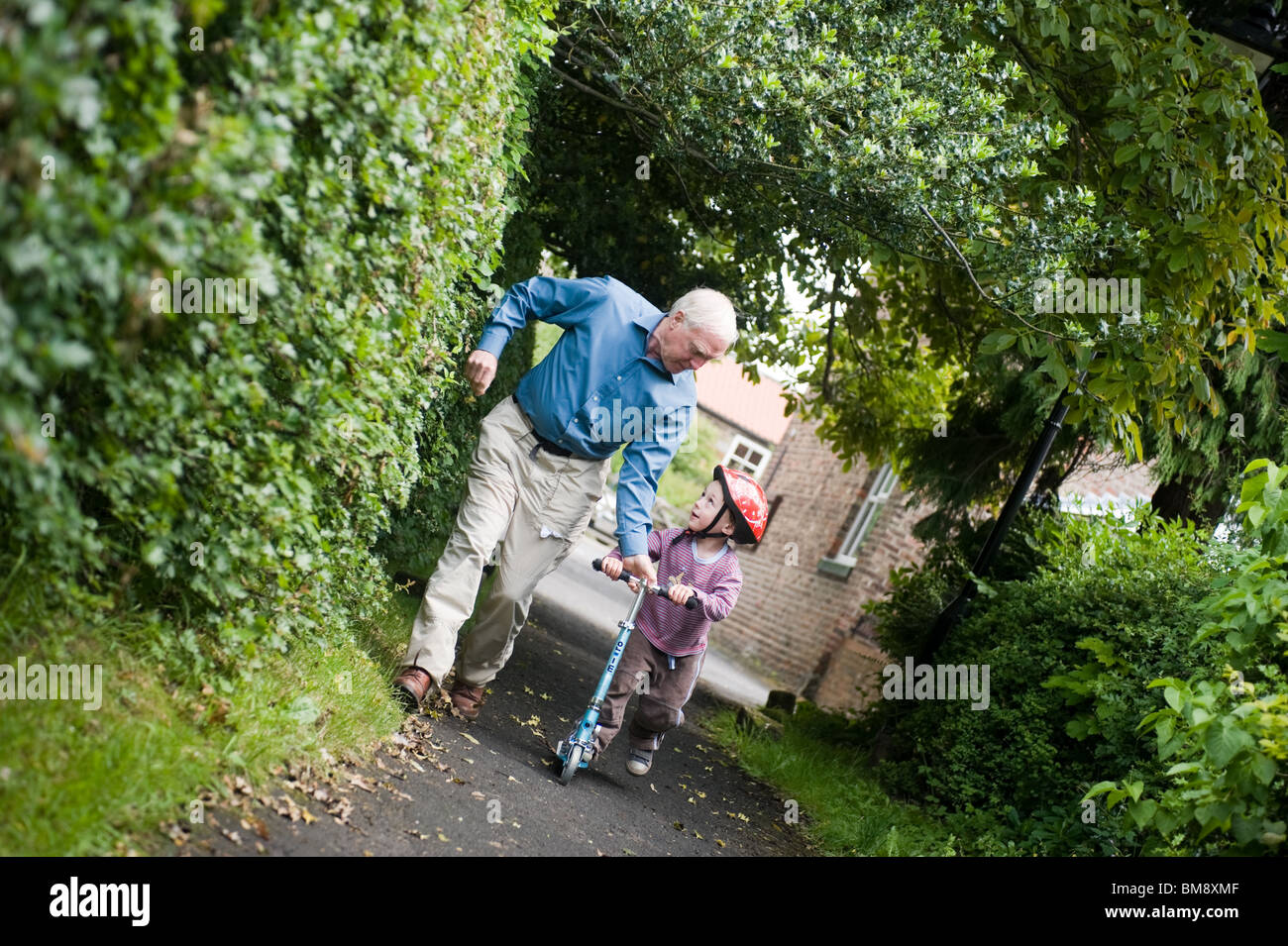 grandfather helping his grandson ride his new scooter Stock Photo - Alamy