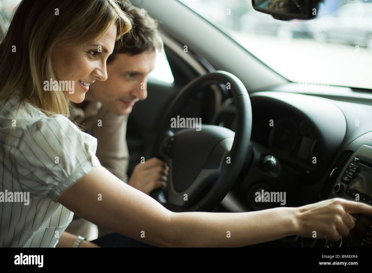 Couple checking out new car interior in dealership showroom Stock Photo ...