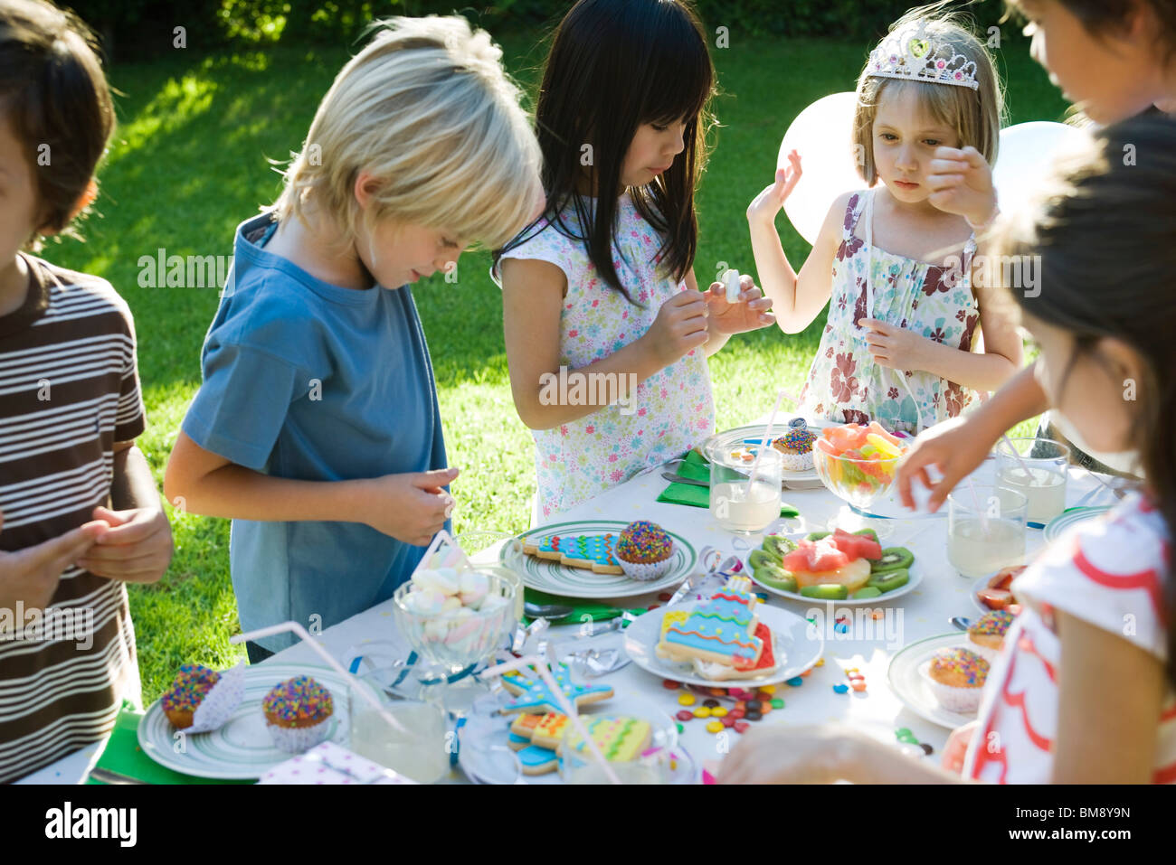 Children selecting sweets from table at outdoor birthday party Stock ...