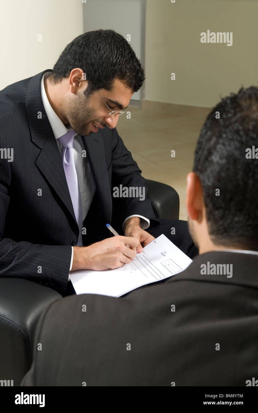 Two businessmen signing contract sitting hi-res stock photography and ...