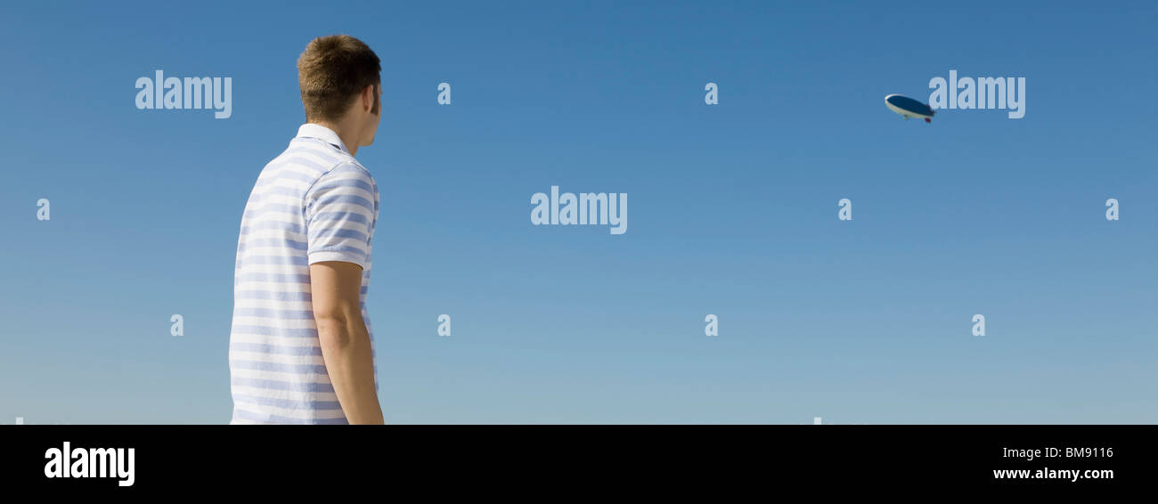 Man looking at blimp in sky Stock Photo - Alamy