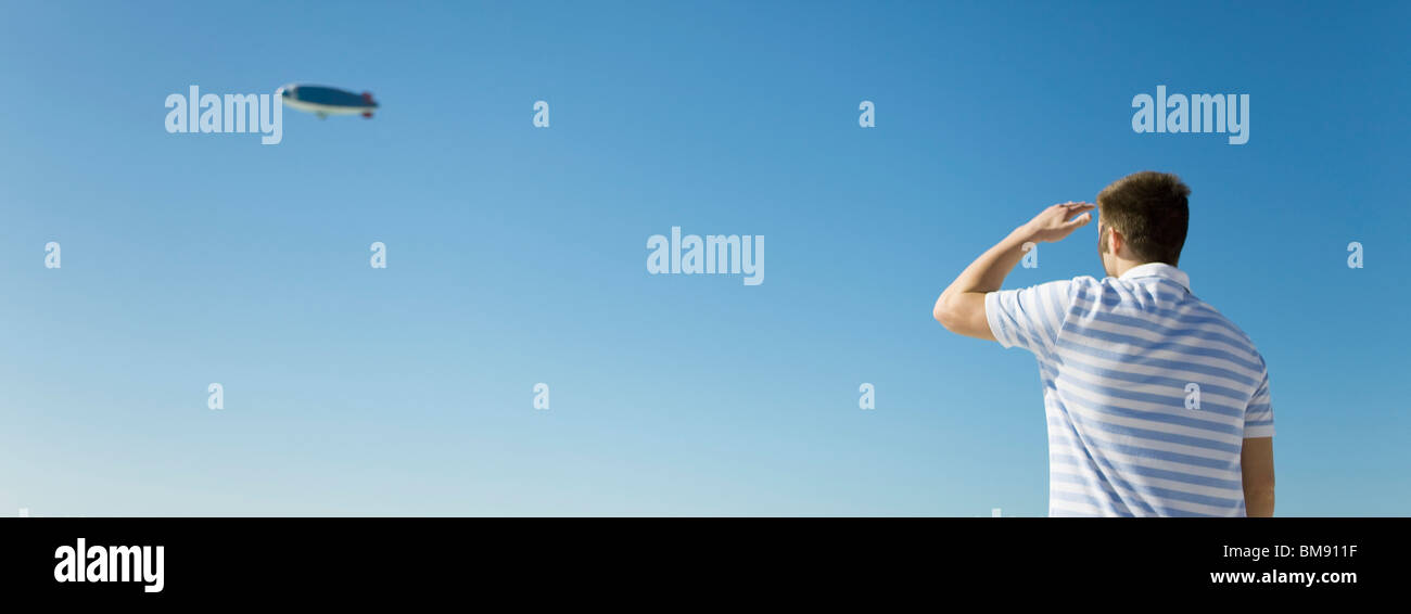 Man looking at blimp in sky Stock Photo - Alamy