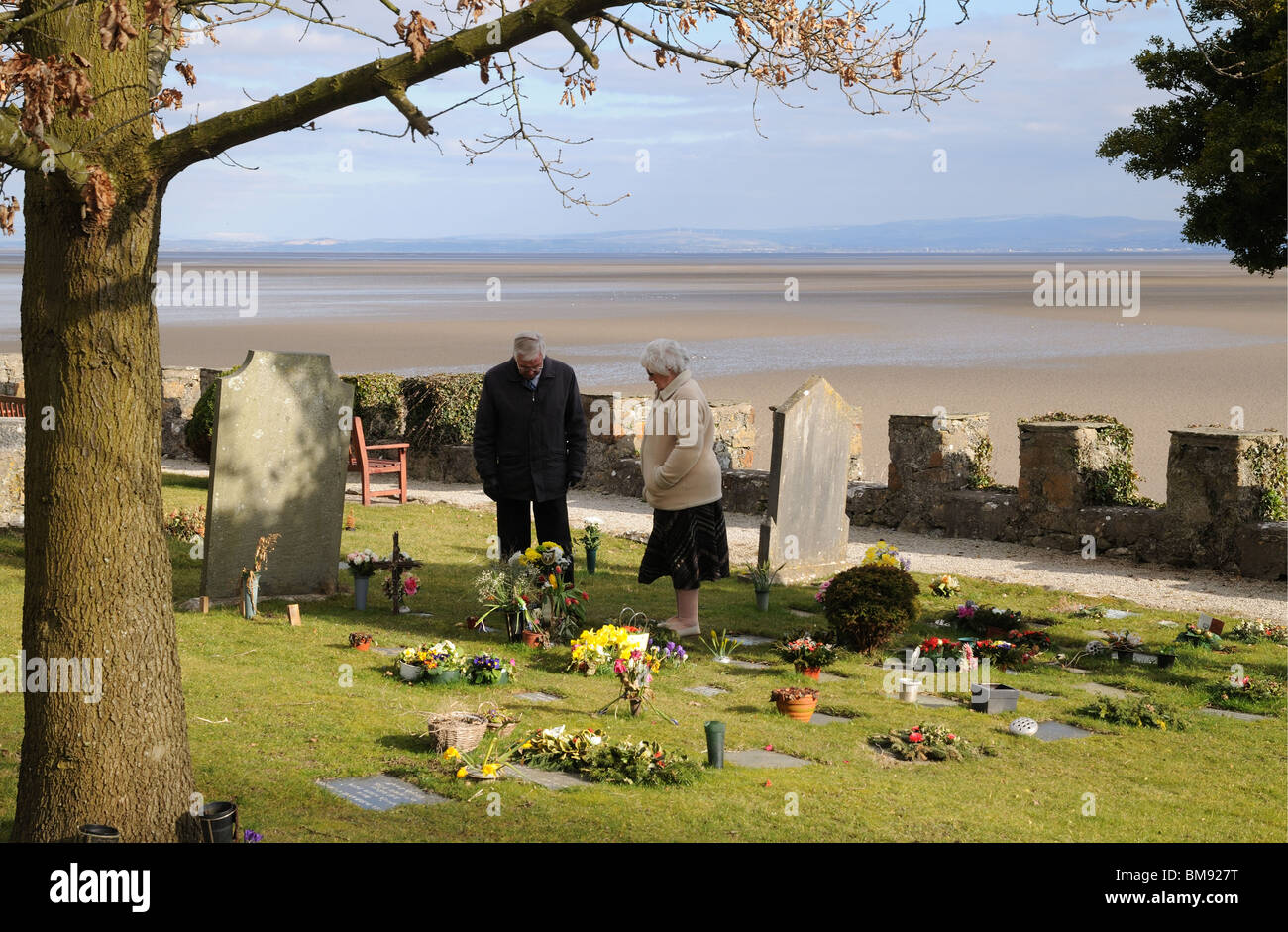 Elderly couple grieving at graveside in graveyard of St Cuthbert’s ...