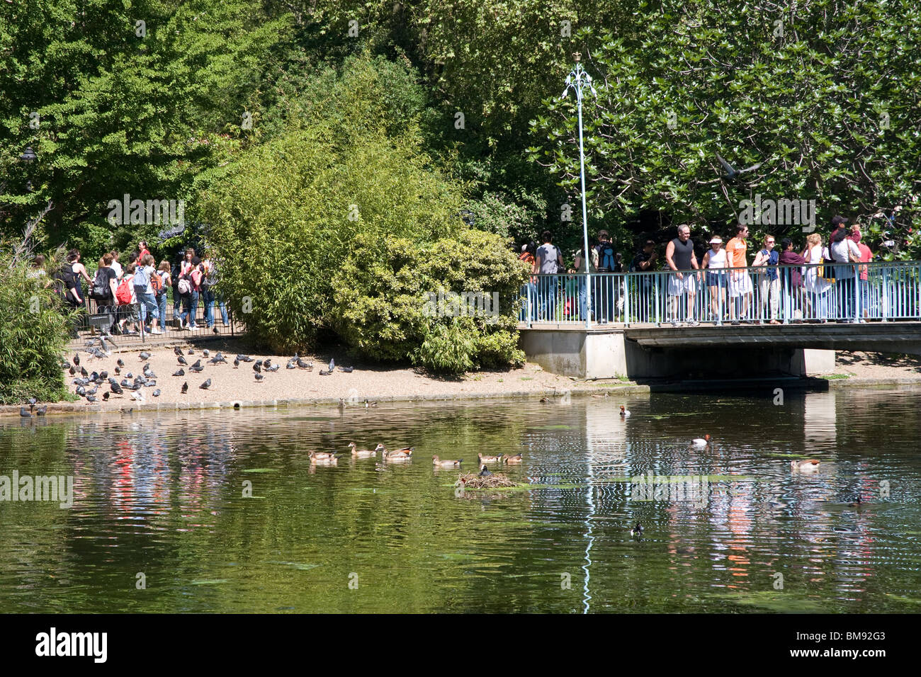crowd people path flowers lake trees bridge water Stock Photo - Alamy