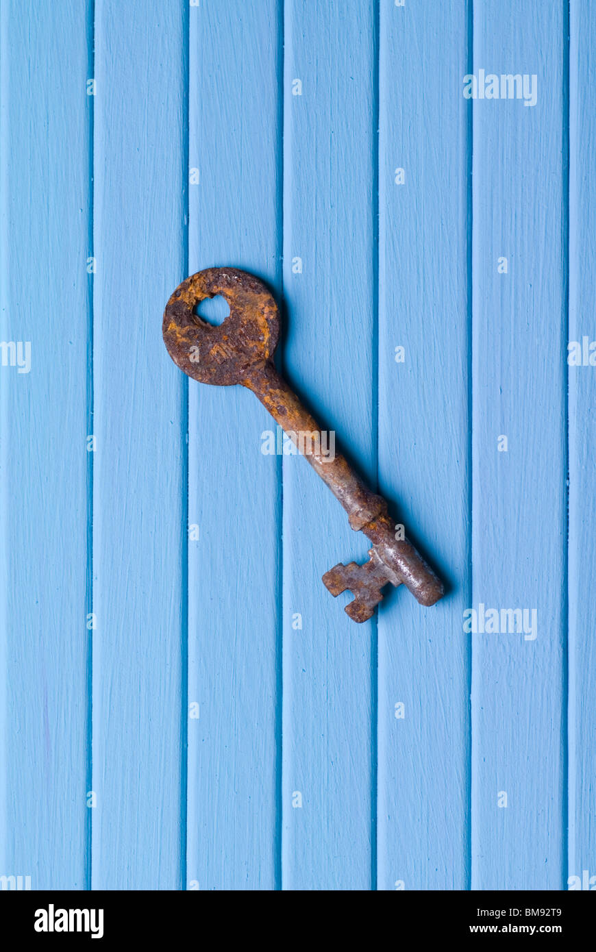 Old abandoned rusted key over a blue wooden background Stock Photo - Alamy