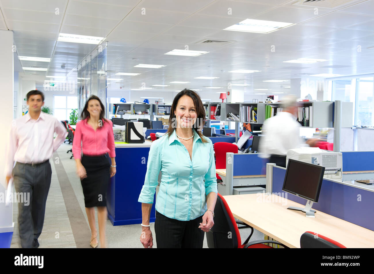 Female office worker with blurred colleagues Stock Photo - Alamy