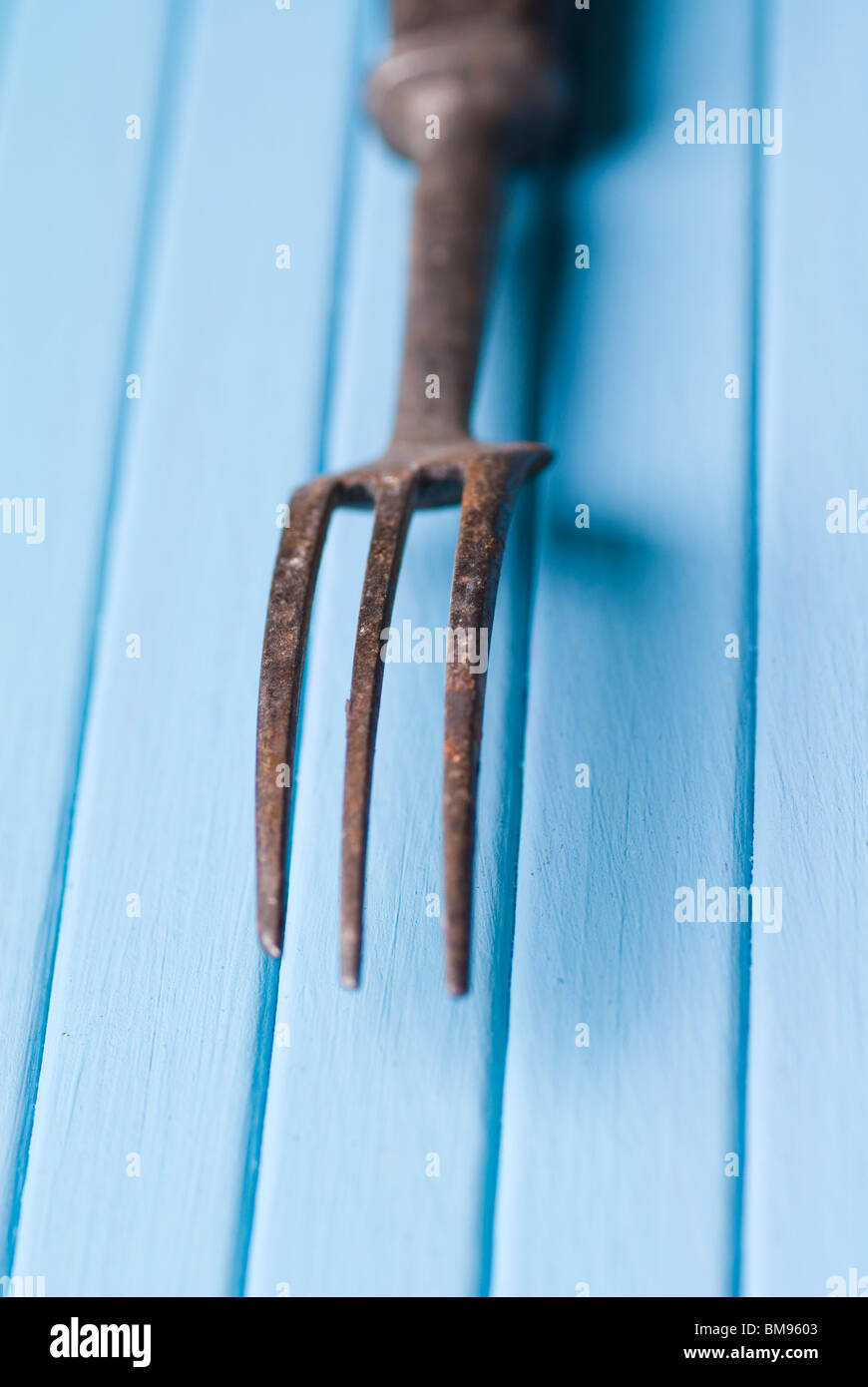 Old fashioned fork rusted over a blue wooden background Stock Photo - Alamy
