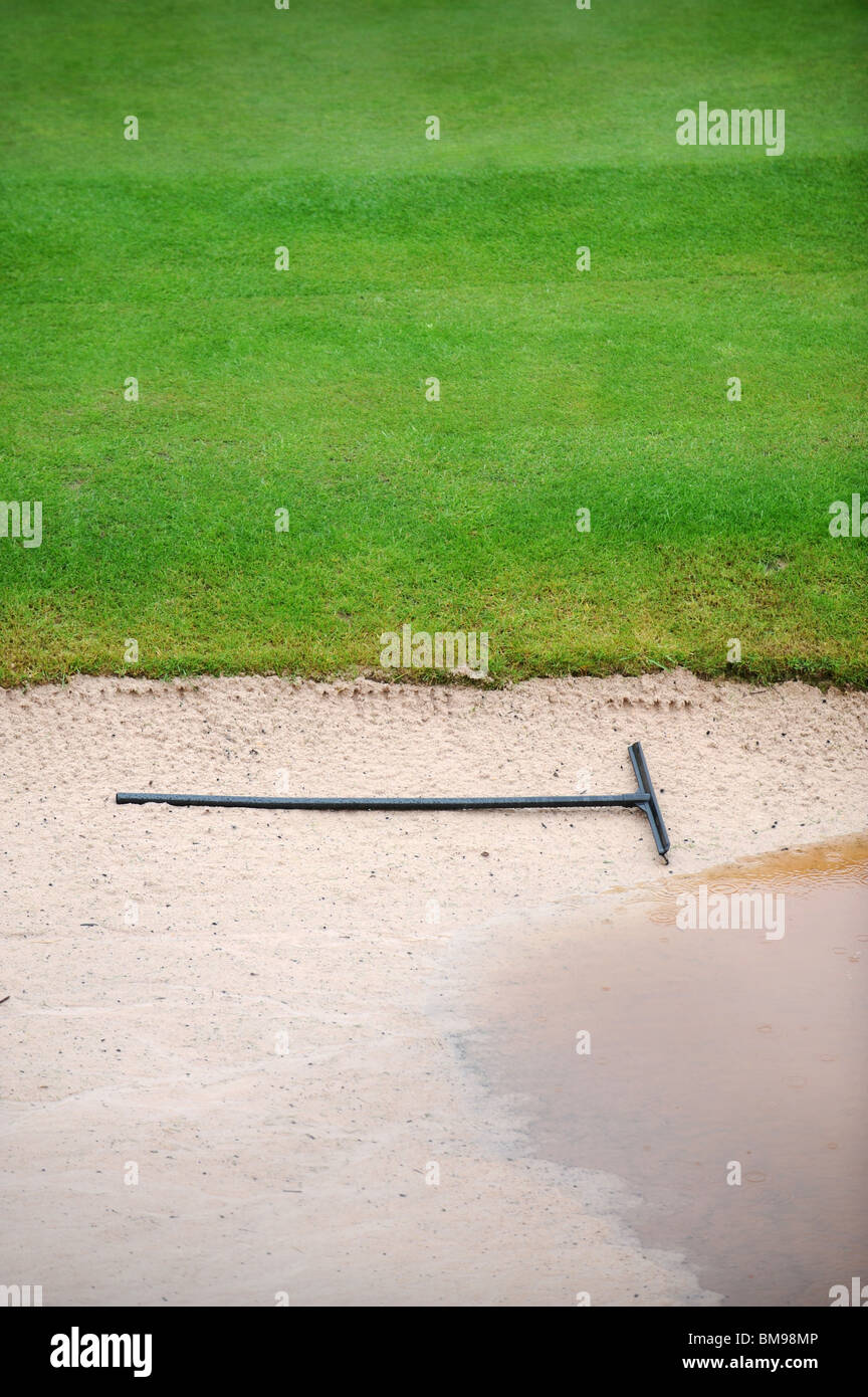 A rake in a waterlogged bunker during a downpour at the Celtic Manor ...